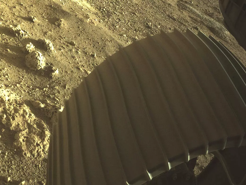 Perseverance priekinis dešinysis ratas su įdomiomis uolomis fone. (Nuotrauka: NASA / JPL)