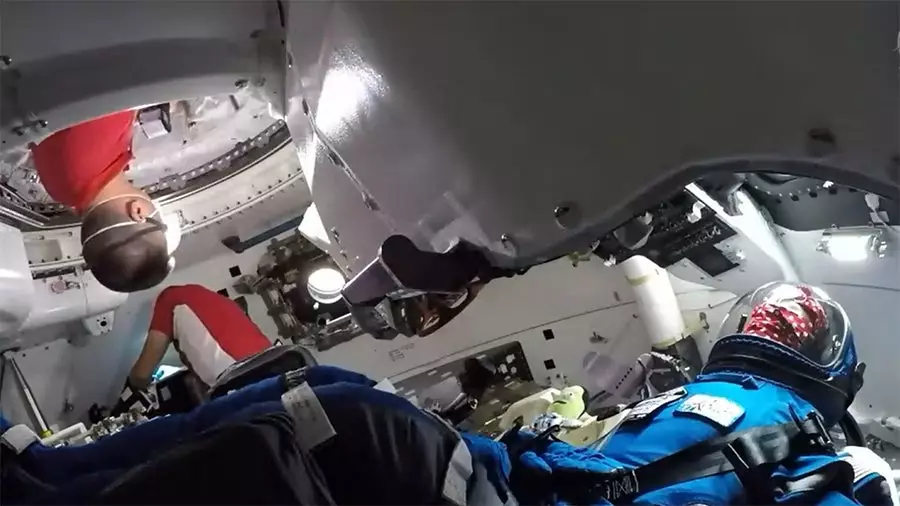 NASA-astronauter inspicerer Starliner-interiøret med Rosie the Rocketeer (en dukke) stadig fastspændt til sit sæde.