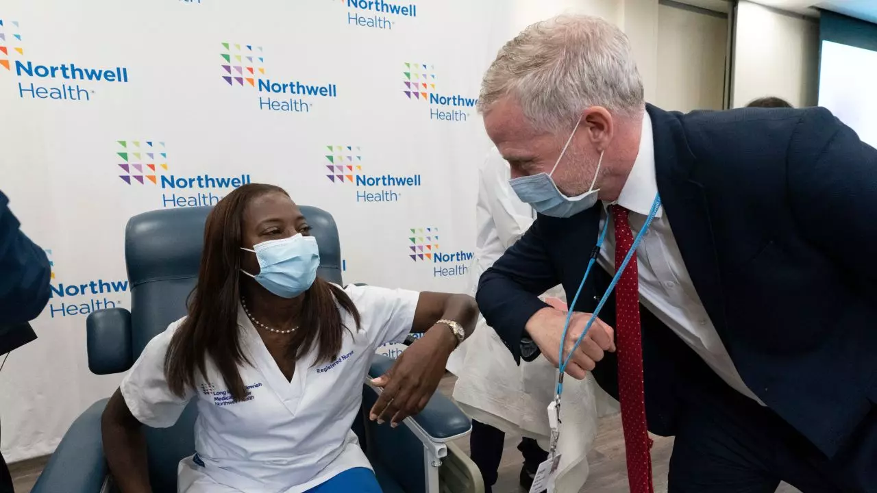 看護師のサンドラ・リンゼイは、2020年12月14日、ニューヨーク市のクイーンズ地区にあるロングアイランドジューイッシュメディカルセンターでcovid-19ワクチンを接種された後、病院の広報担当者であるジョセフケンプと肘をぶつけました。