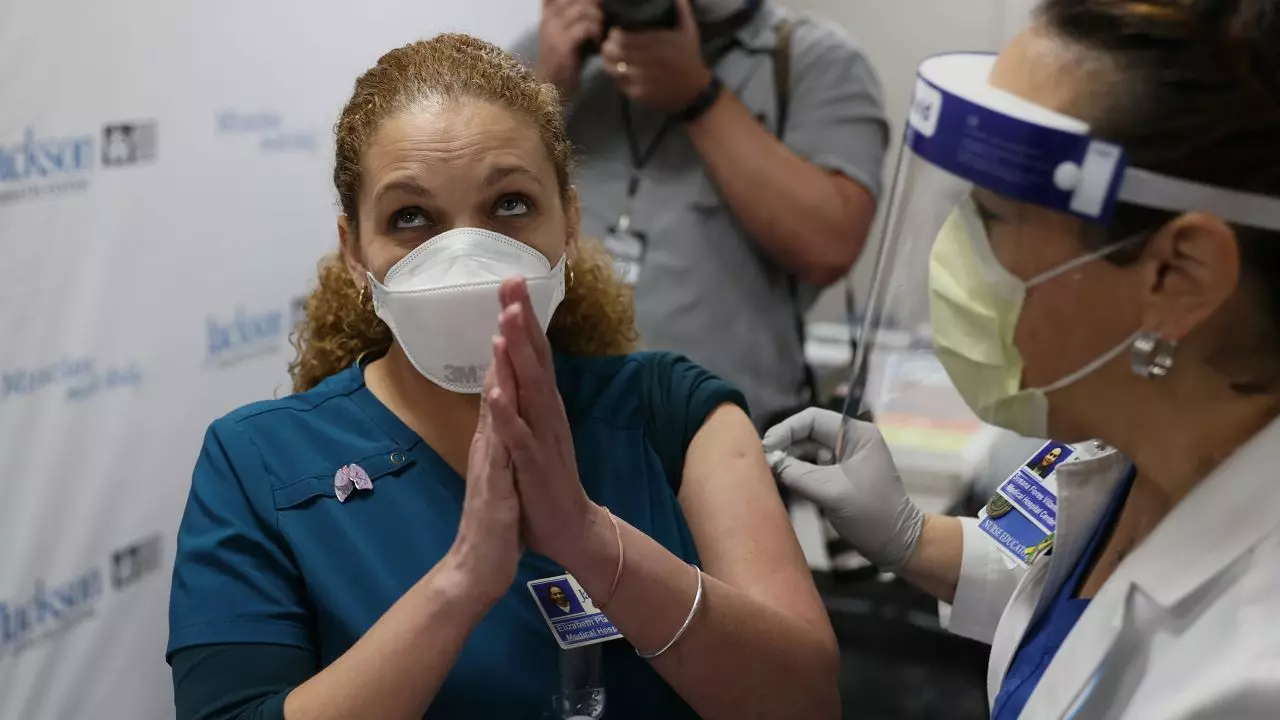 2020 年 12 月 15 日，杰克逊医疗系统 RRT 医疗医院中心的伊丽莎白普拉森西亚在迈阿密杰克逊纪念医院接受了来自杰克逊医疗系统的注册护士 Susana Flores Villamil 的辉瑞/BioNtech covid-19 疫苗后双手合十，佛罗里达州。