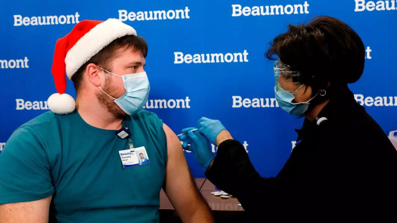 Здравствени радник у Бомонту Тимоти Дехарт (лево) прима своју прву дозу вакцине Пфизер/БиоНТецх цовид-19 од стране Керолин Вилсон у њиховом сервисном центру у Саутфилду, Мичиген, 15. децембра 2020.