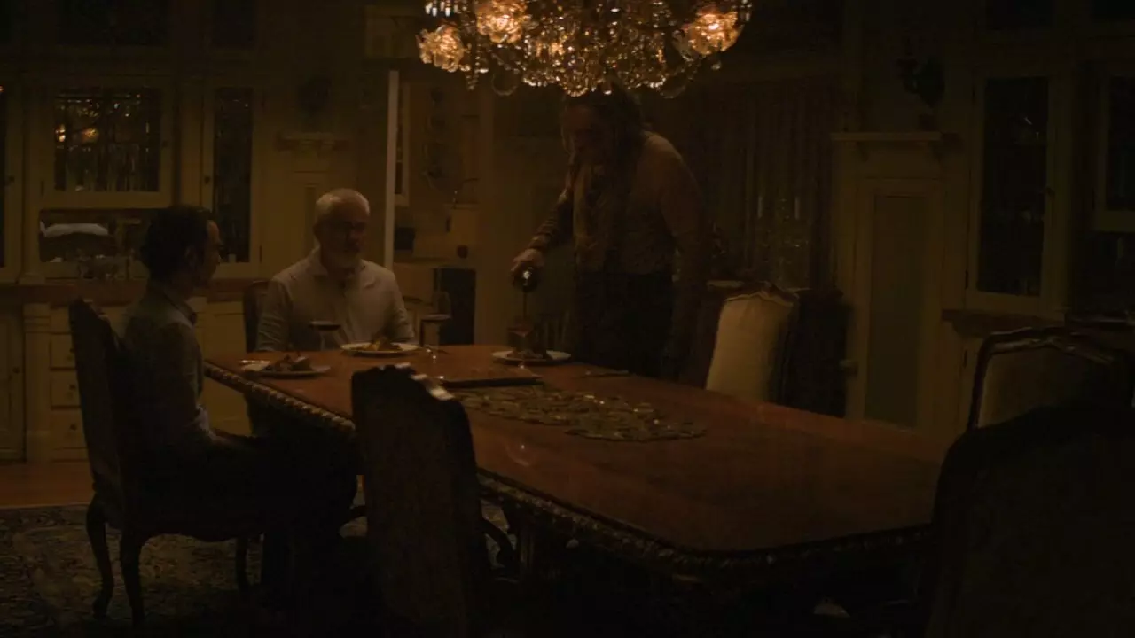ニコラス・ケイジは自分のためにグラスワインを注ぎ、テーブルに座っている男性と若い男性が彼を待っています