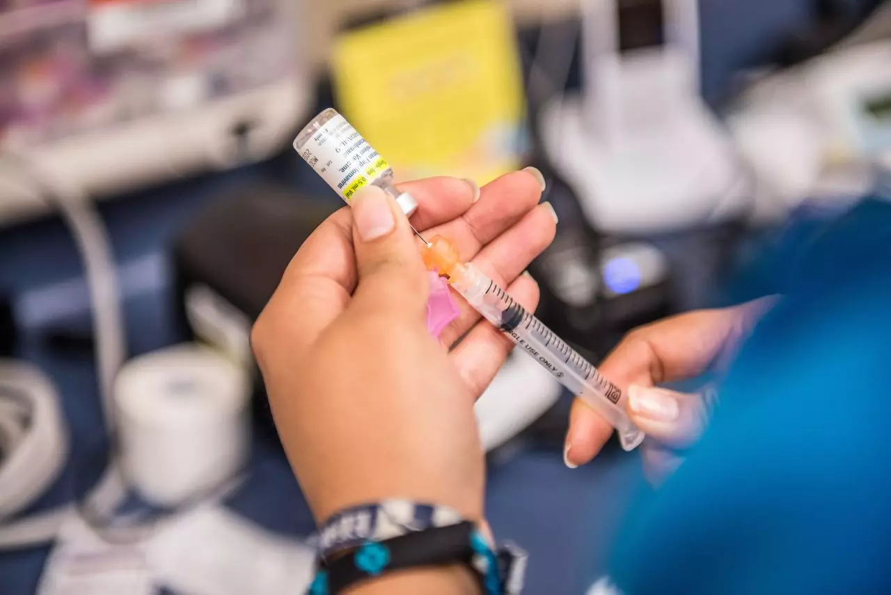 Медицина қызметкері HPV вакцинасының егуін дайындап жатыр.