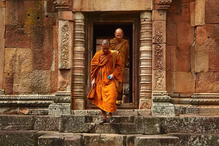 兩個身穿橙色長袍的僧侶走下水泥樓梯。