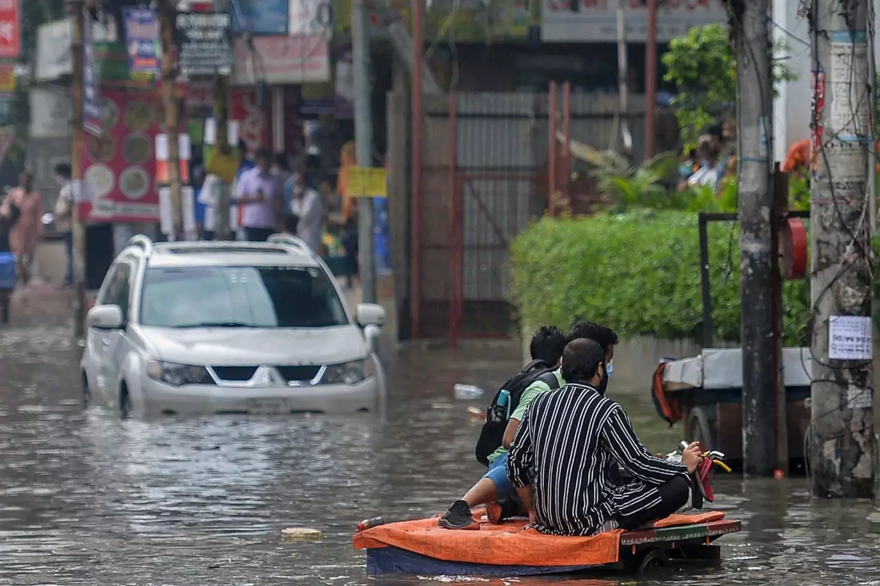 Abagenzi bari kuri cycle-rickshaw banyura mumuhanda wuzuye amazi nyuma yimvura nyinshi yabereye i Dhaka ku ya 4 Nyakanga 2021. (Ishusho: Munir Uz zaman, Getty Images)