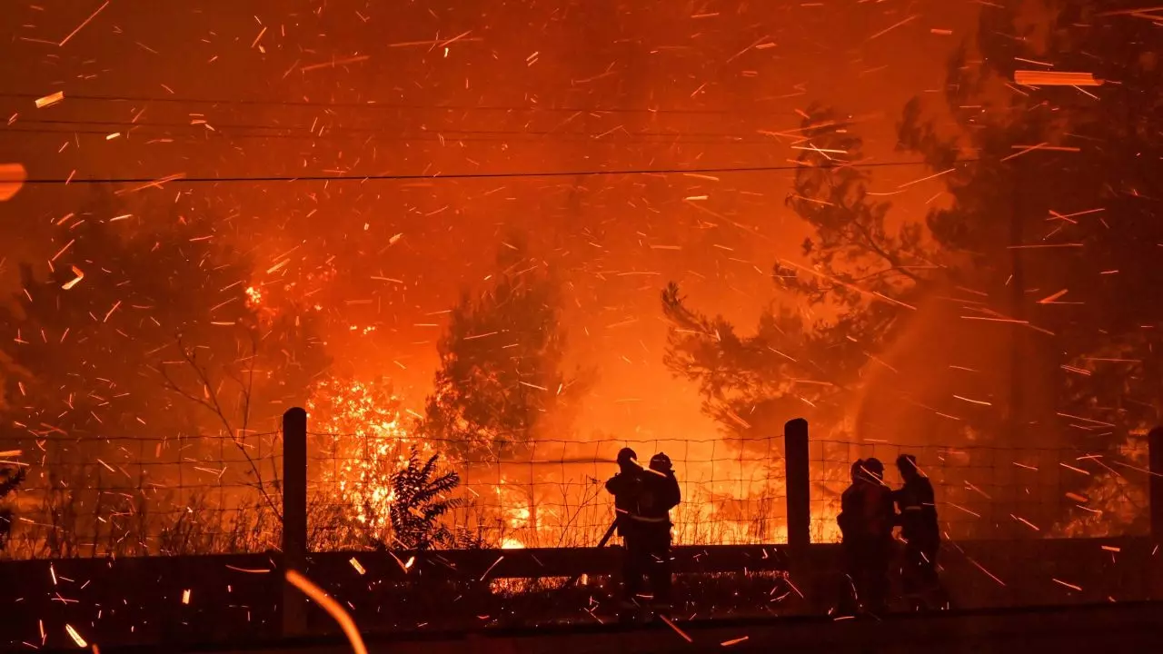 소방관들이 2021년 8월 5일 그리스 아테네 북부의 고속도로 위로 화염이 퍼지면서 산불을 진압하려고 노력하고 있습니다.