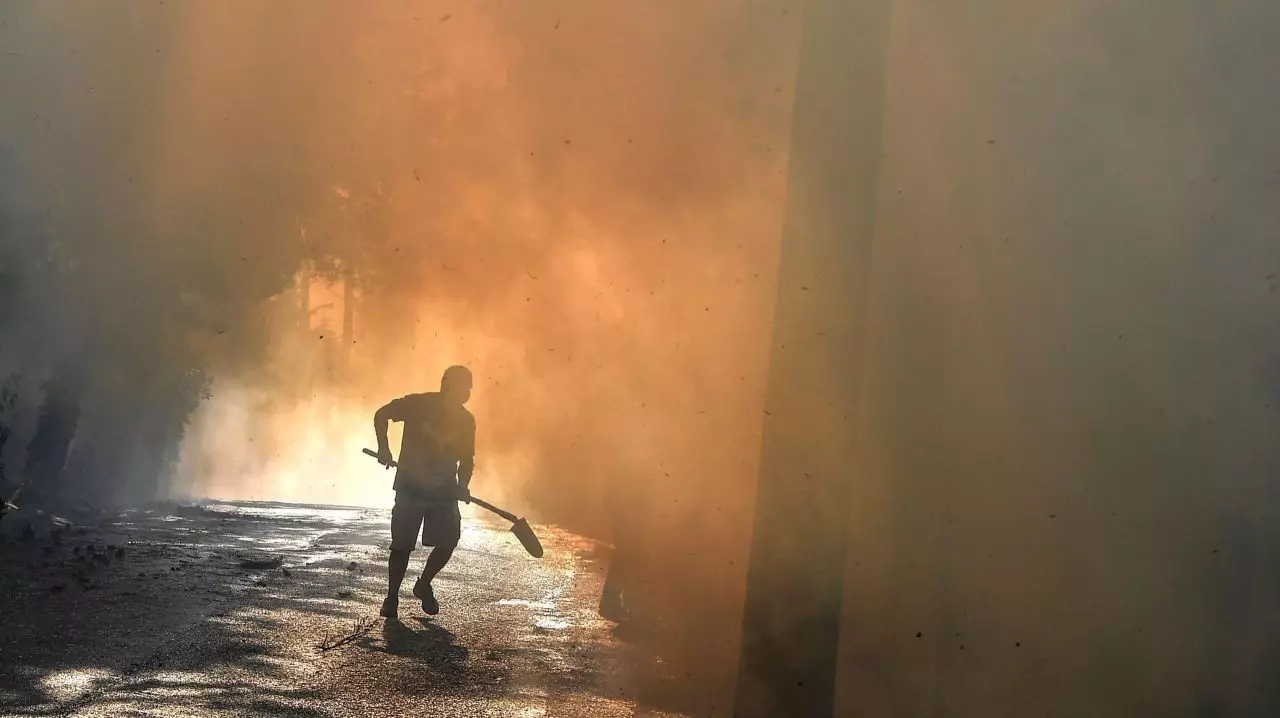 Un veciño local corre para loitar contra un incendio en Thrakomakedones, preto do monte Parnitha, ao norte de Atenas, Grecia, o 7 de agosto de 2021.