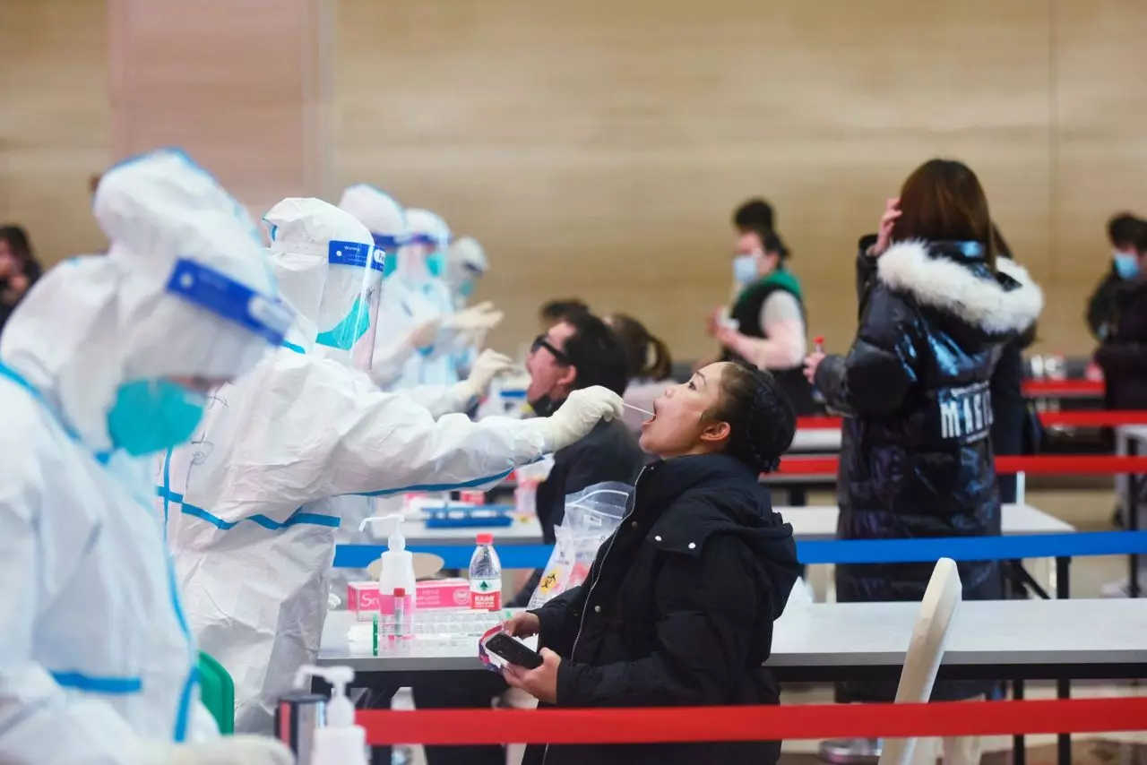 Un traballador médico toma mostras de cotonete durante unha proba obrigatoria de covid-19 a traballadores das industrias de servizos da área comercial de Wulin na cidade de Hangzhou, na provincia de Zhejiang, no leste de China, o mércores 15 de decembro de 2021.