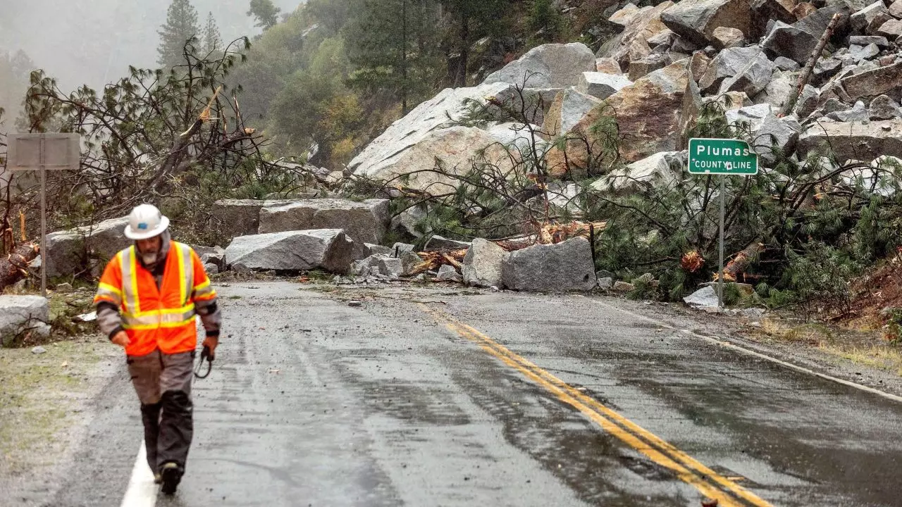 Matt Martin, mpanara-maso ny fikojakojana Caltrans, mandeha amin'ny fihotsahan'ny tany mandrakotra ny Highway 70 ao amin'ny faritra Dixie Fire.