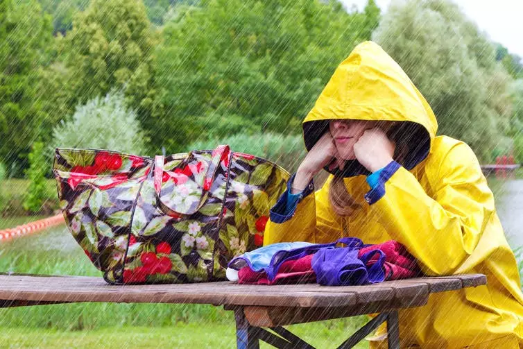 Imagem de uma mulher sentada na chuva.