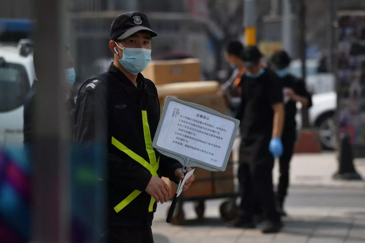 En säkerhetsvakt håller en skylt som talar om att foton är förbjudna utan tillstånd, utanför en butik hos svenska klädjätten H&M i Peking den 25 mars 2021,
