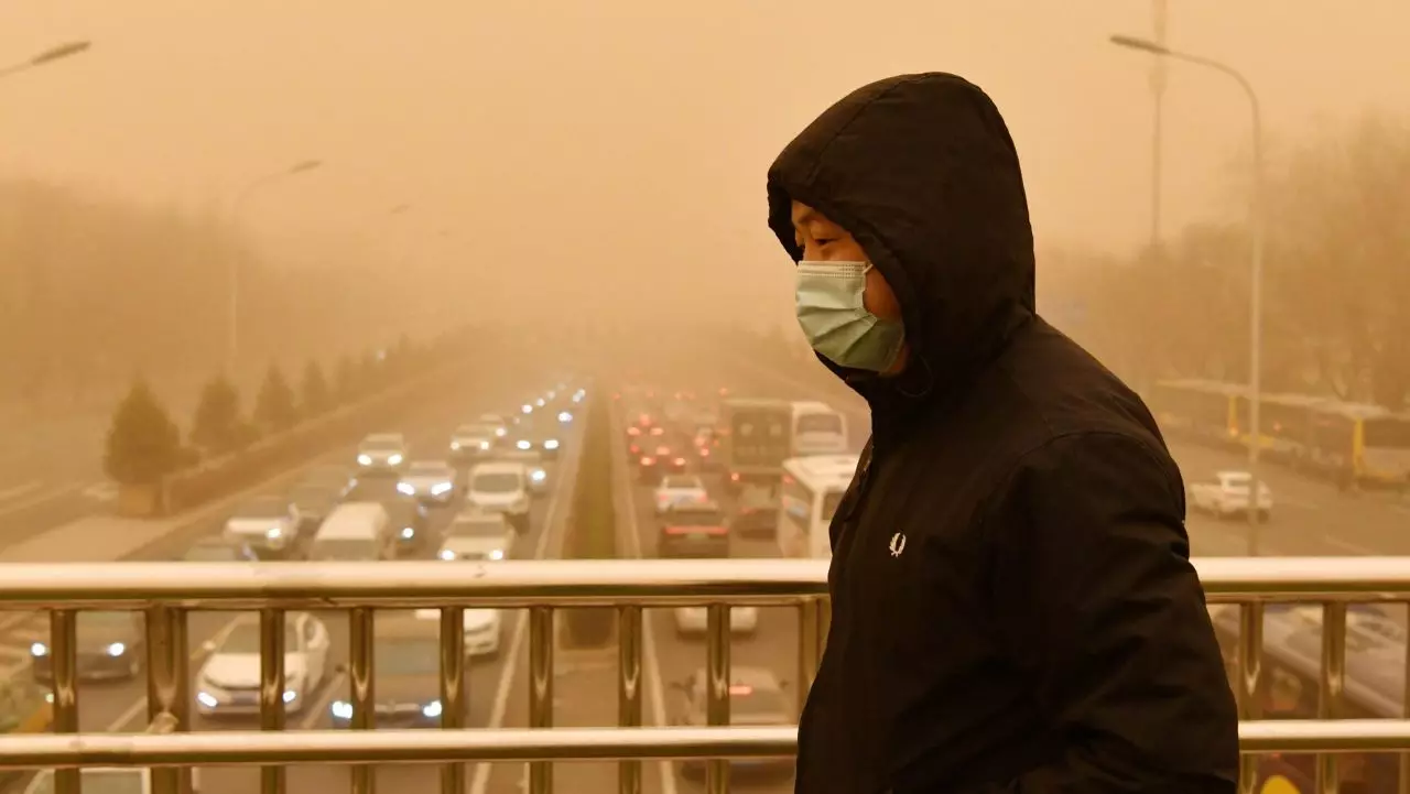 Een man loopt op een voetgangersoverbrugging tijdens een zandstorm in Peking terwijl het verkeer op de achtergrond kruipt op 15 maart 2021.