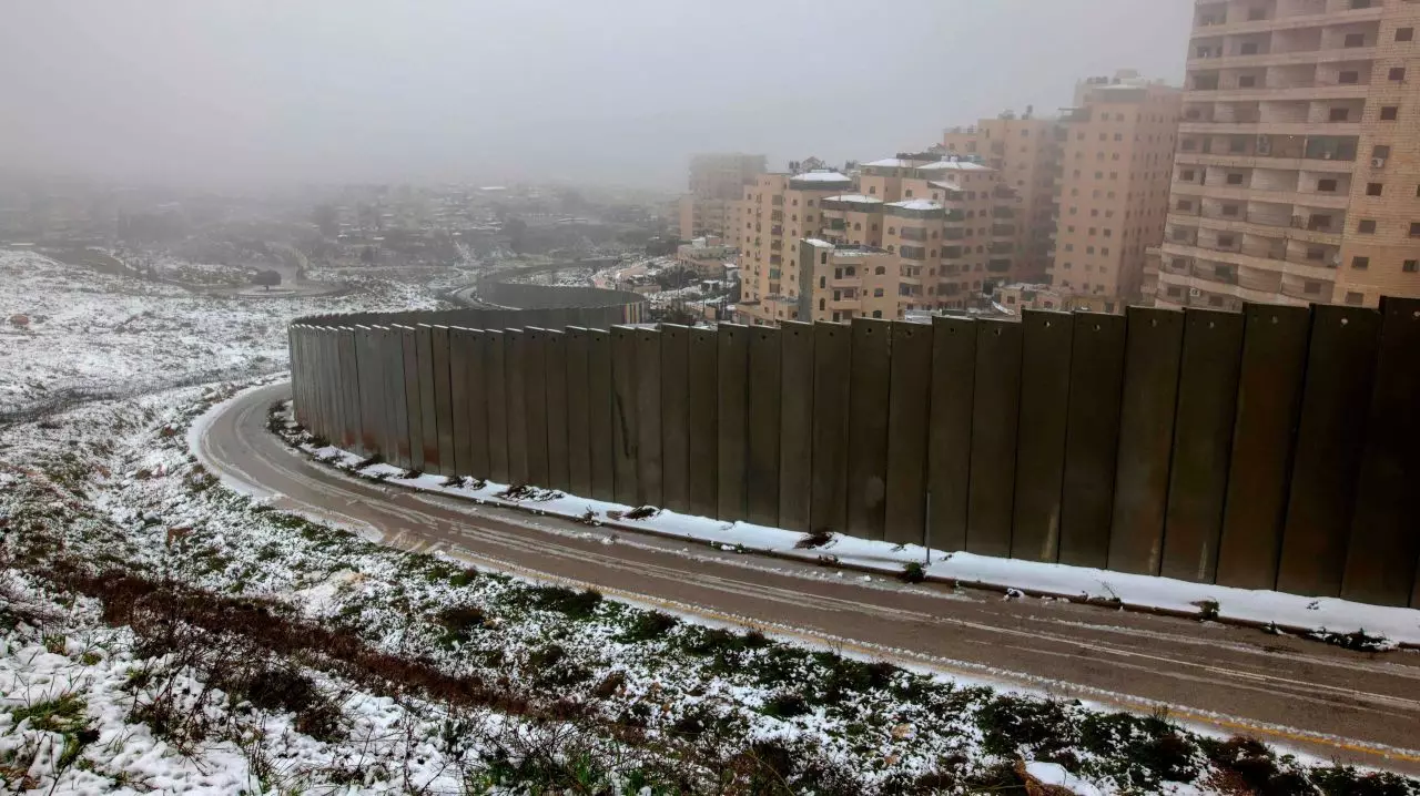 Čiastočný pohľad ukazuje kontroverzný separačný múr Izraela a palestínsky utečenecký tábor Shuafat po hustom snežení v Izraelom anektovanom východnom sektore Jeruzalema 18. februára 2021.