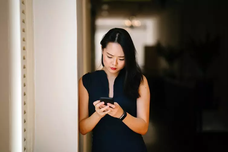 Femme regardant son téléphone avec une expression sérieuse.