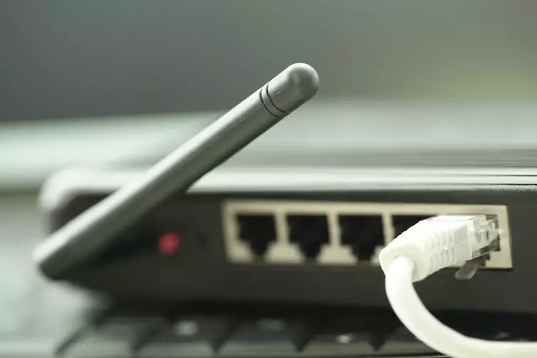 Arrière d'un petit routeur Internet domestique avec antenne Wi-Fi, ports Ethernet et câbles Ethernet