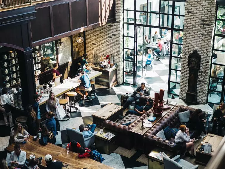 Vue depuis un balcon vers un café animé où la plupart des gens regardent leur téléphone