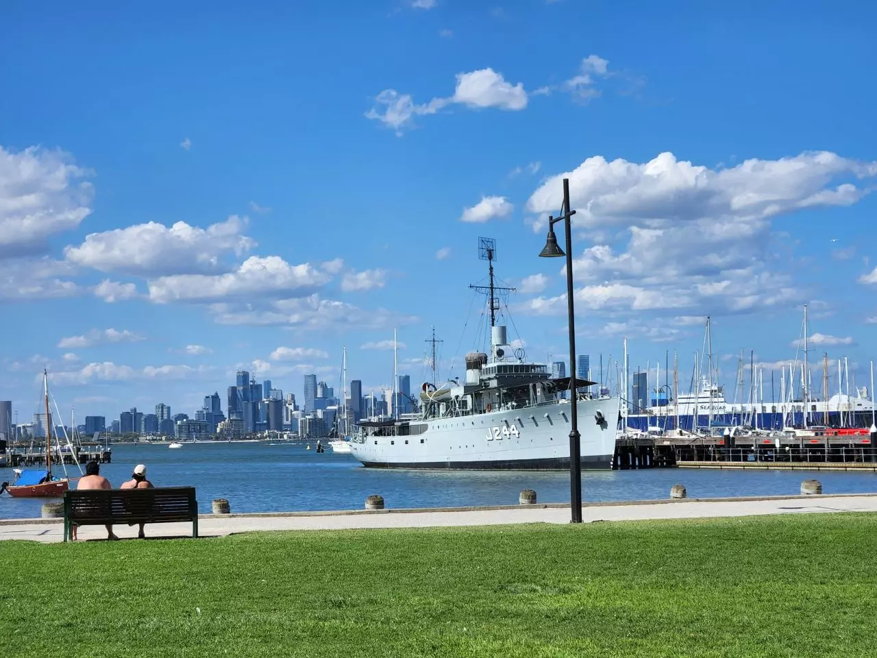 Un barco da mariña nun día soleado co horizonte de Melbourne detrás